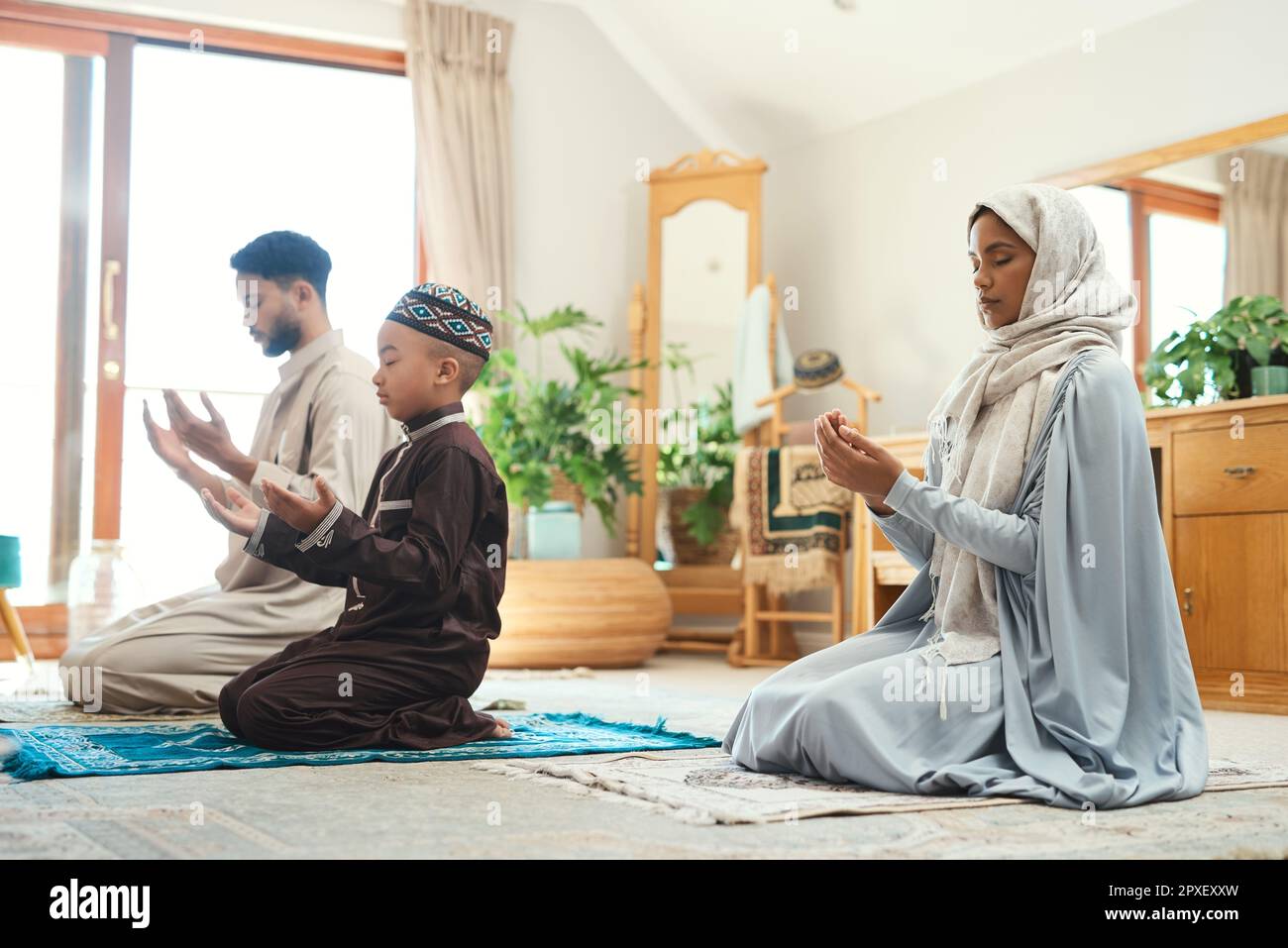 Blessing upon blessings. a young muslim couple and their son praying in ...