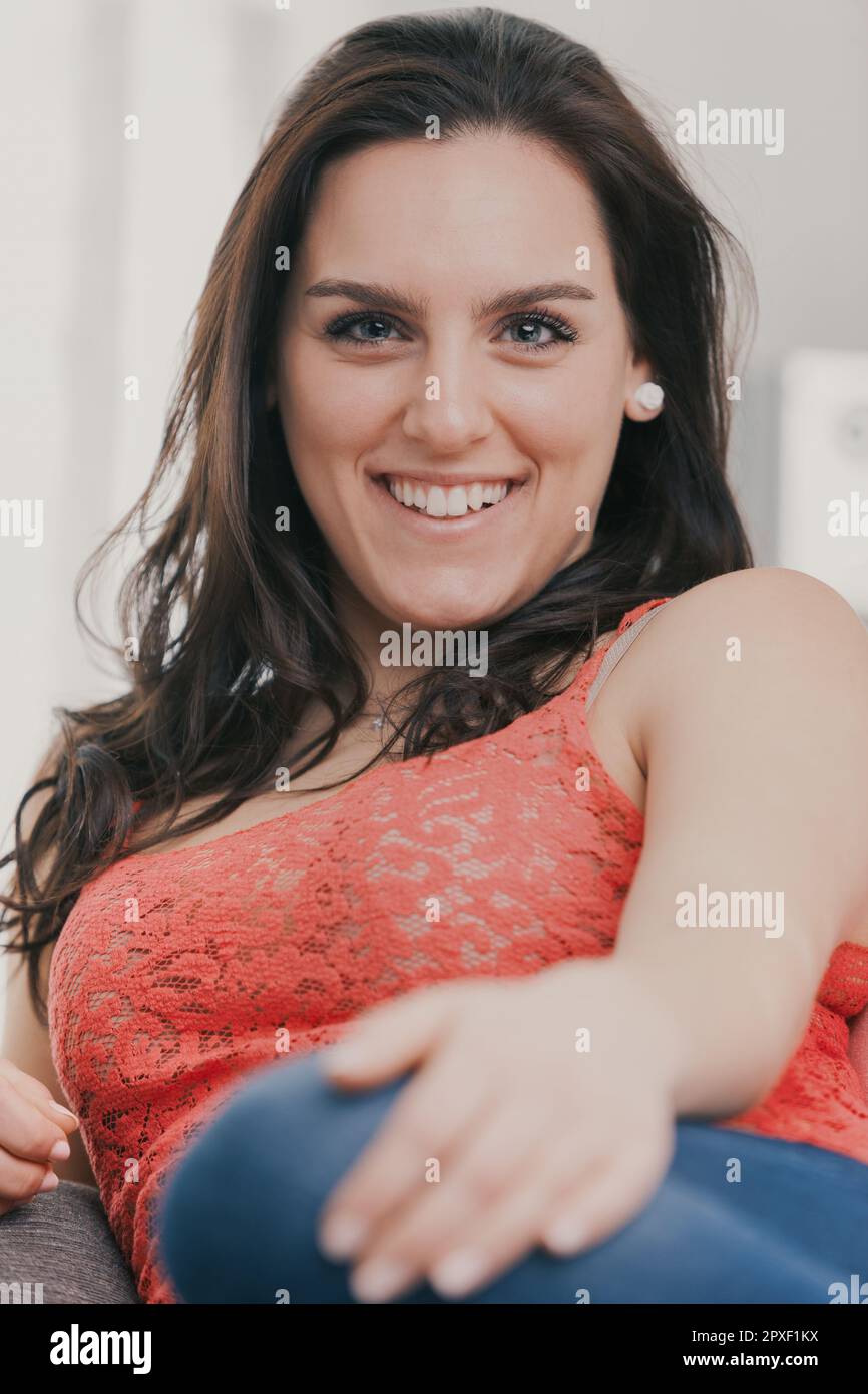 A Woman On The Couch In Her Home With Her Gaze Directed Towards Us And A Big Intense Smile On