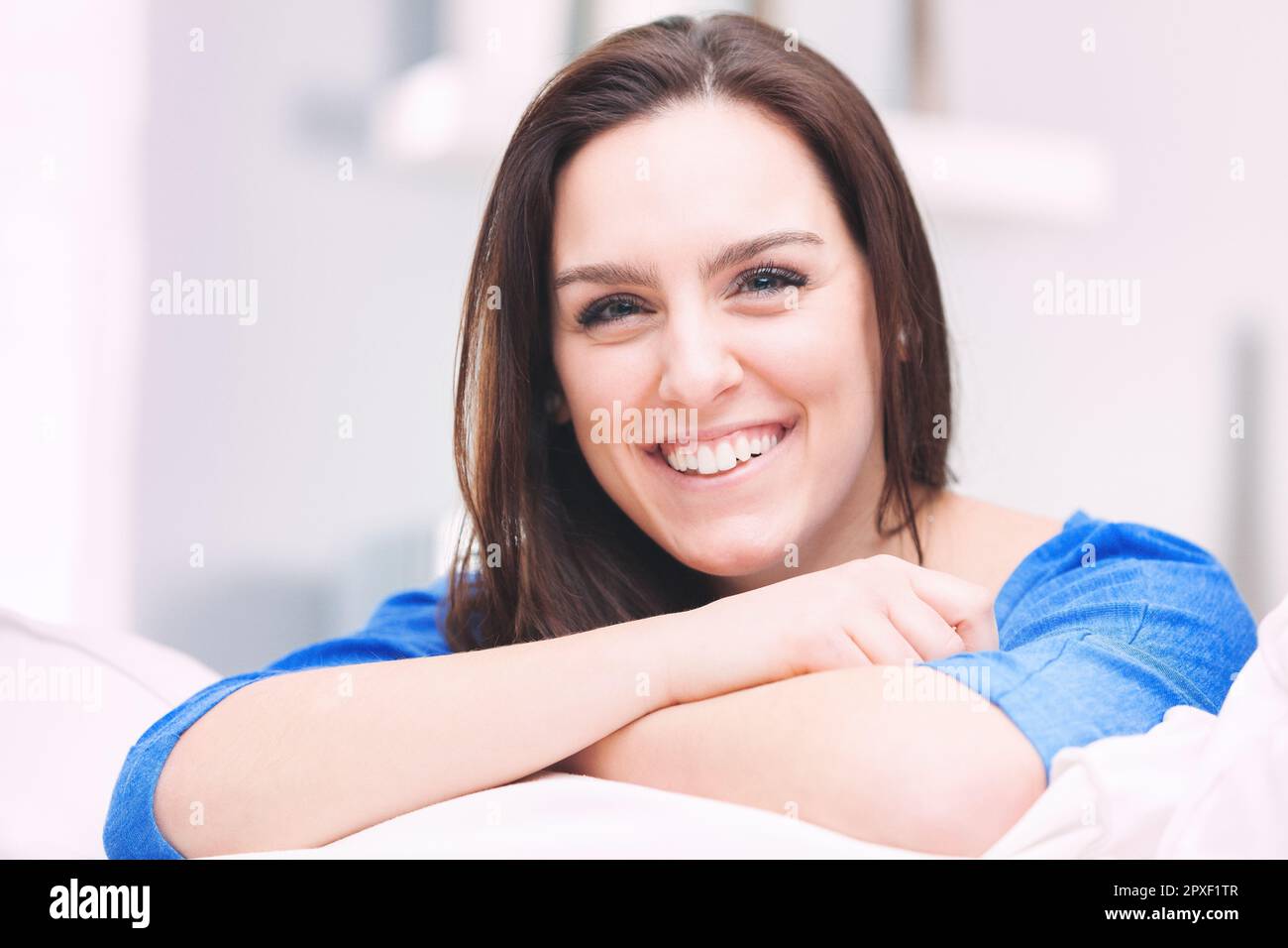 A young, happy, and dreamy woman smiles with her head resting on her ...