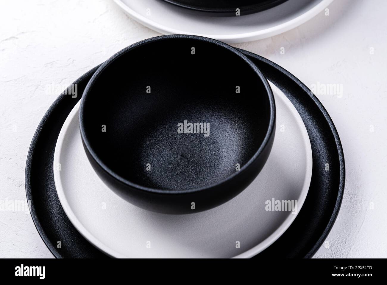 Different black and white empty plates and bowls on a white table Stock ...