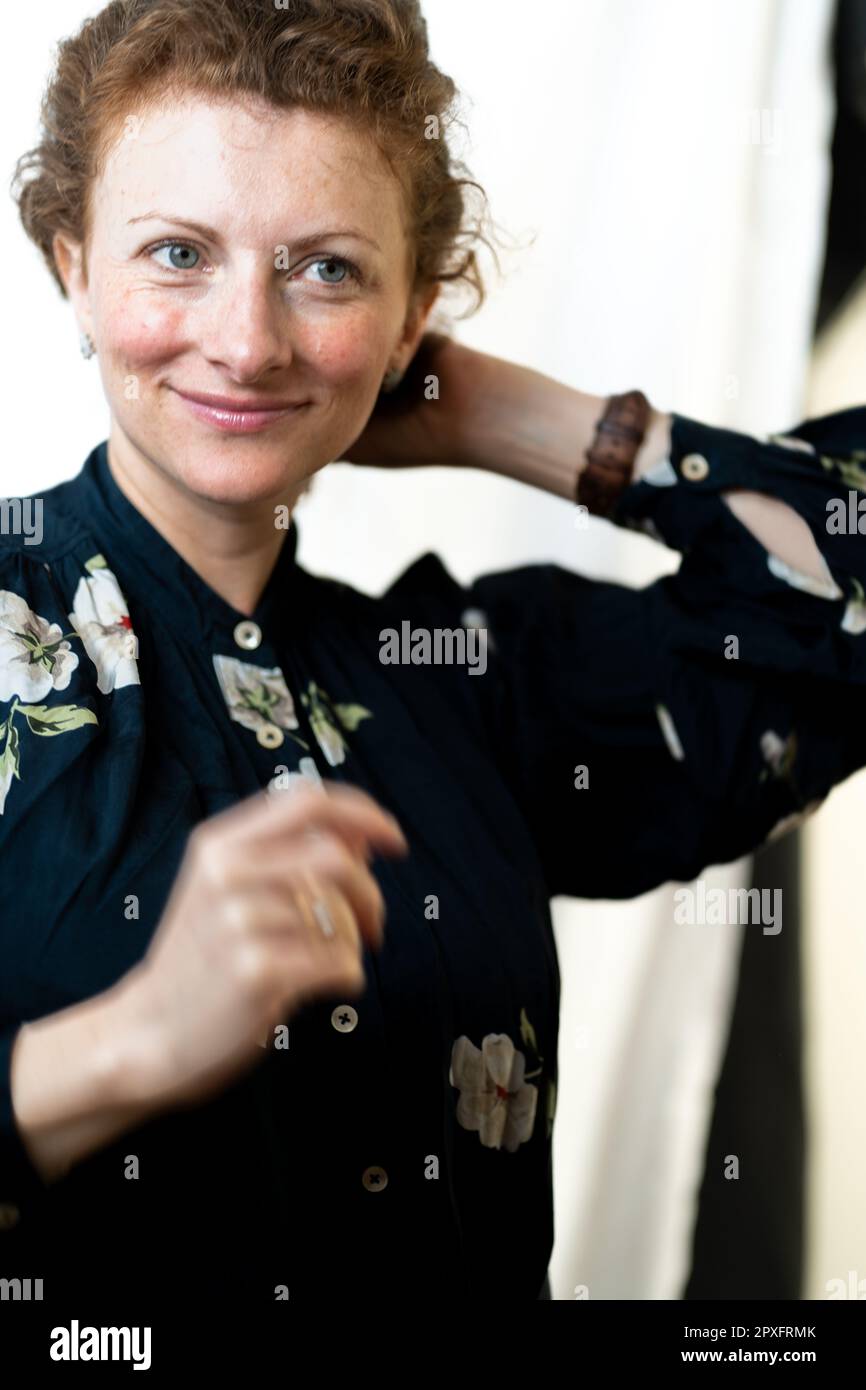 A vertical of a ginger model posing, dressed in an elegant blue shirt ...