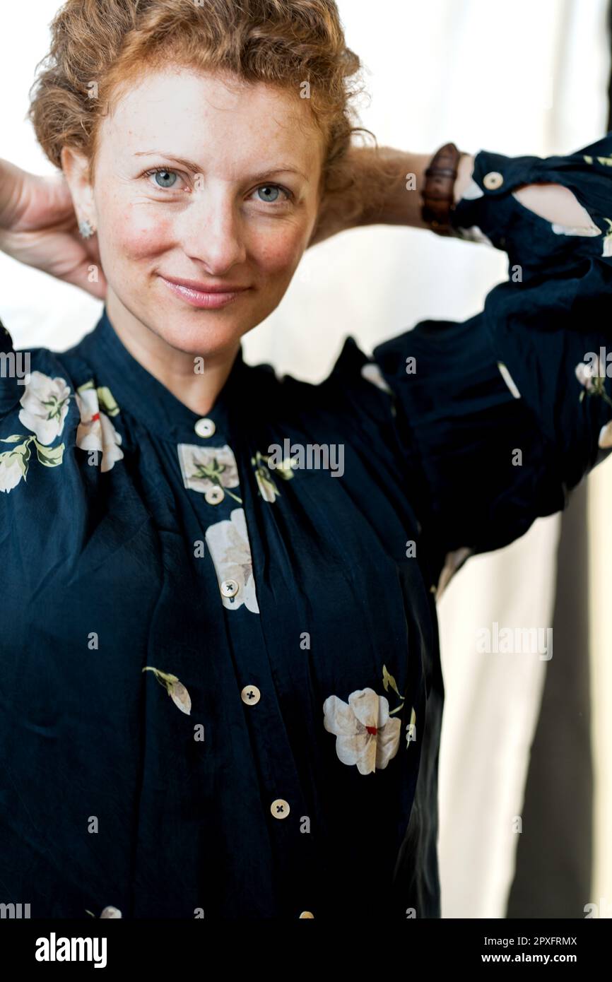A vertical of a ginger model posing, dressed in an elegant blue shirt ...