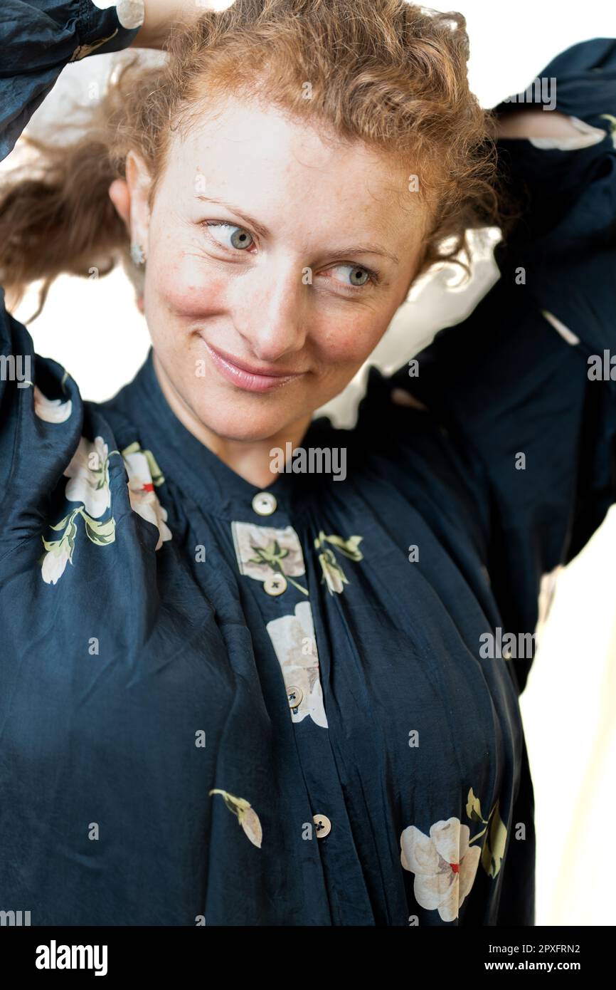 A vertical of a ginger model posing, dressed in an elegant blue shirt ...