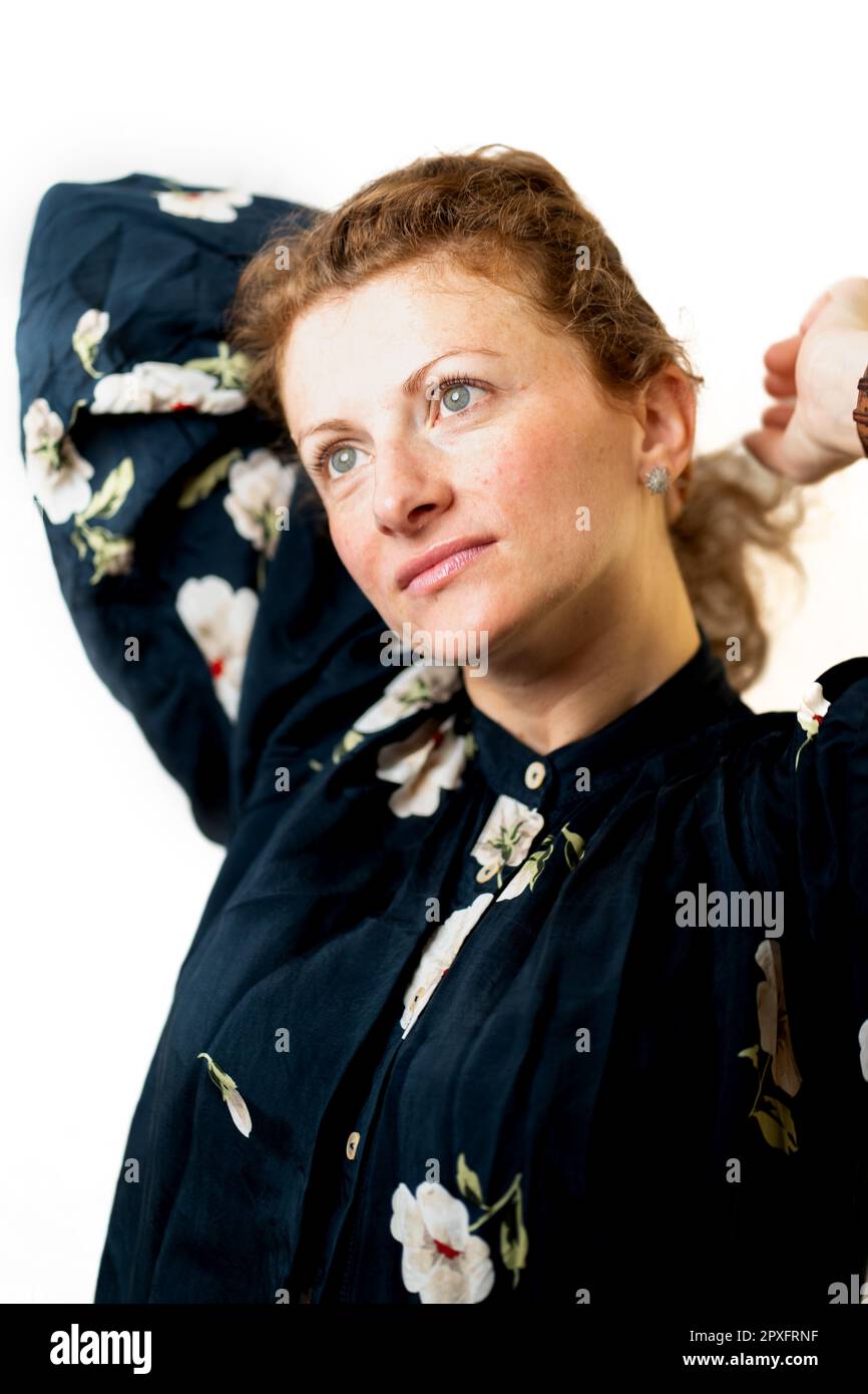 A vertical of a ginger model posing, dressed in an elegant blue shirt ...