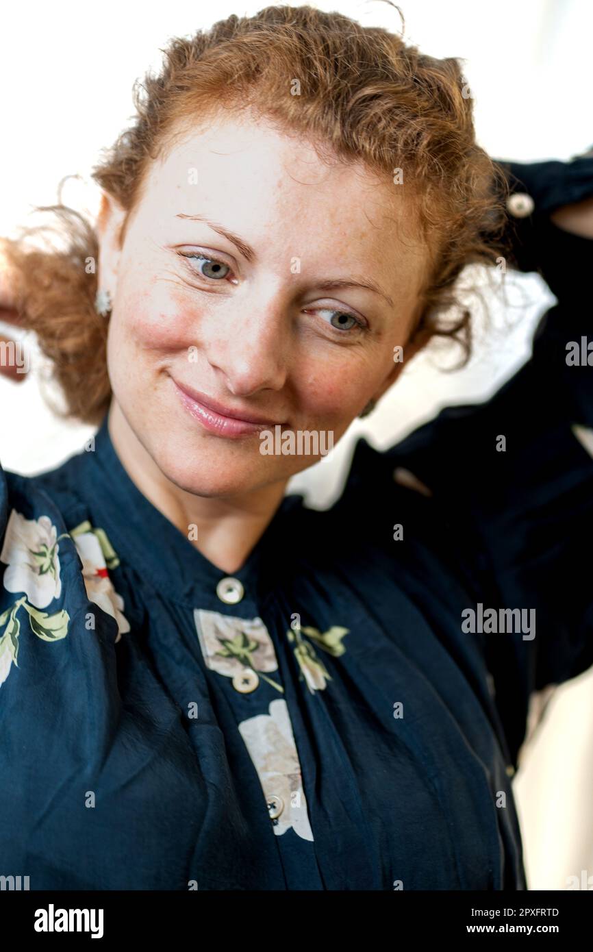 A vertical of a ginger model posing, dressed in an elegant blue shirt ...