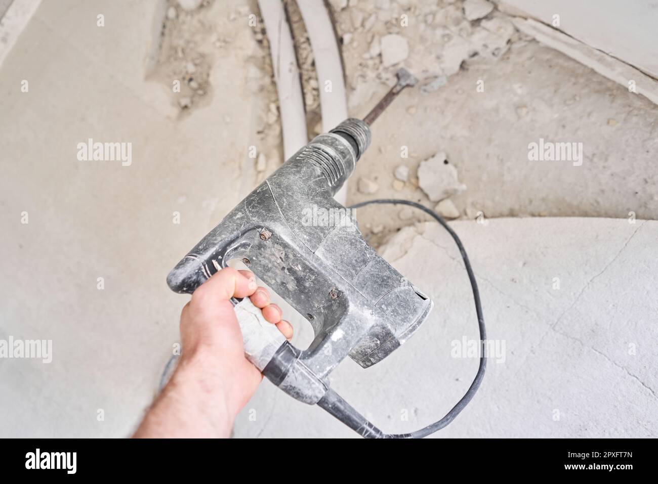 Hammer concrete with a hammer drill to make a hole for heating pipes ...