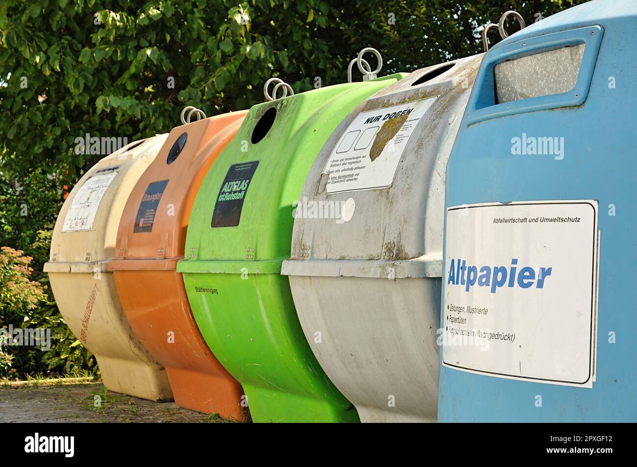 Five colorful metal waste receptacles are arranged in a neat line ...