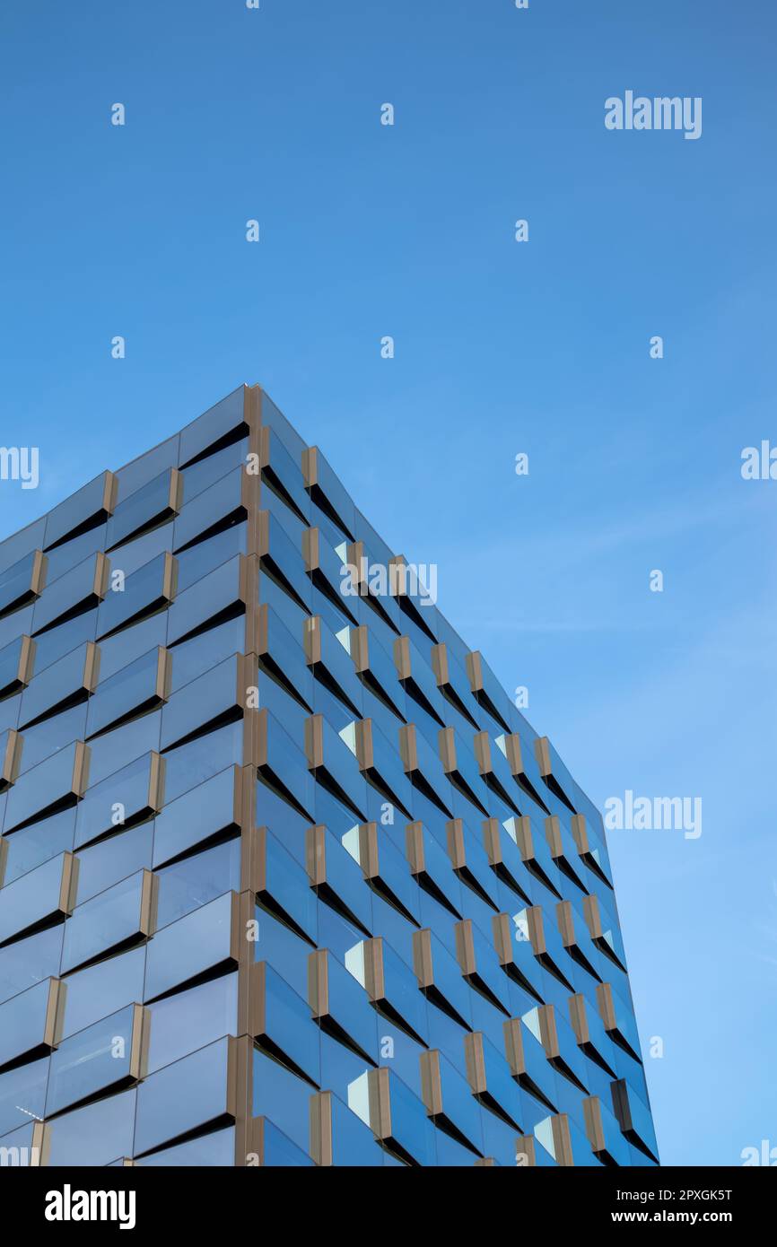 This photo captures a corner of a modern high-rise building, featuring ...