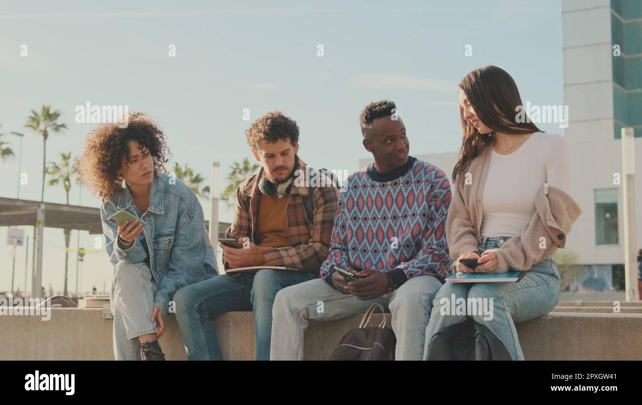 Happy group of friends using phone and smiling together outside ...