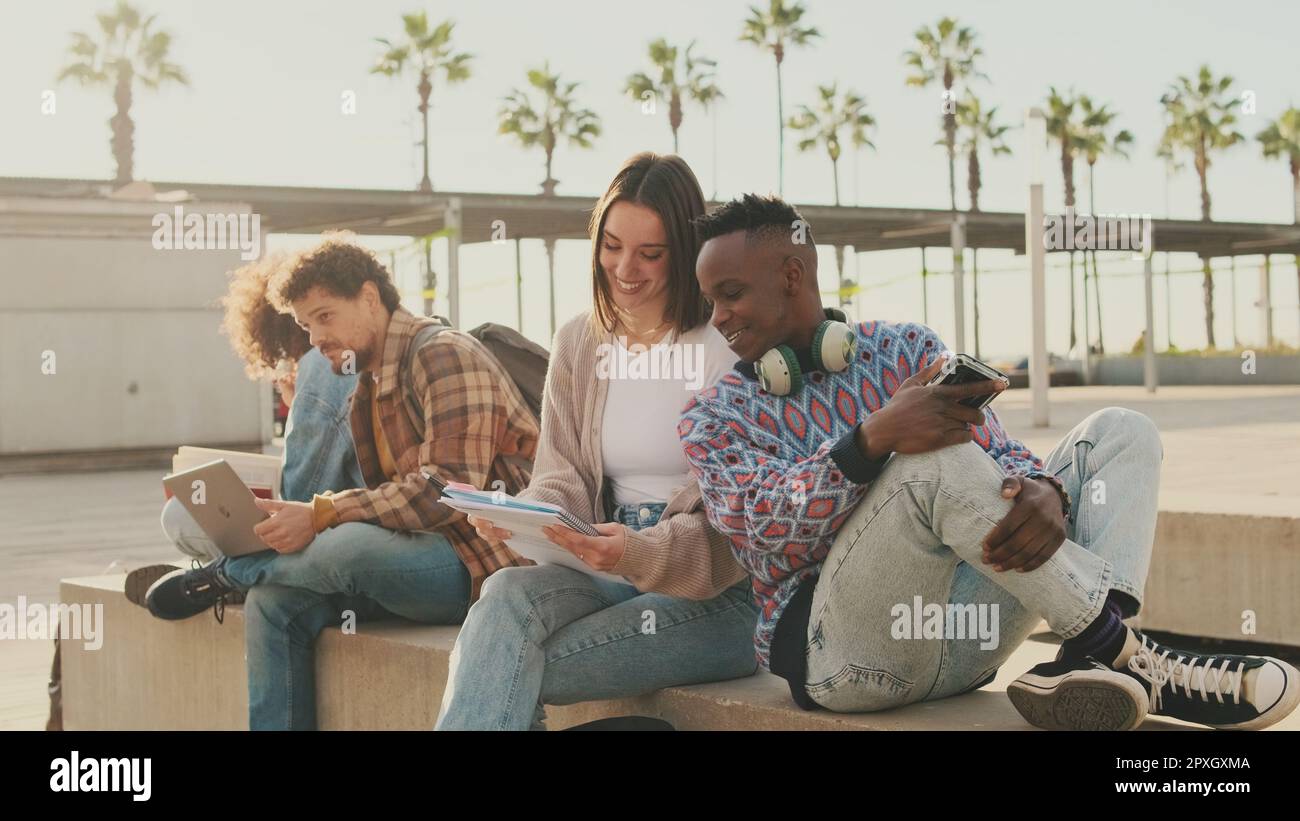 Group of students study while seated outside a university building ...