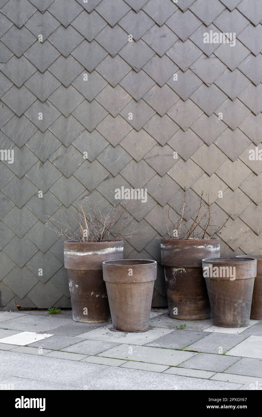 An image of four large brown flower pots placed against a wall in an ...
