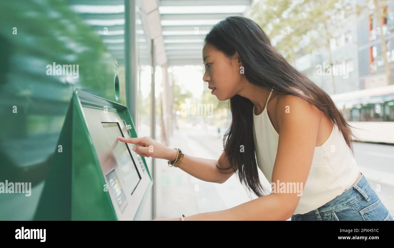 Young woman buying ticket at public transport stop Stock Photo - Alamy