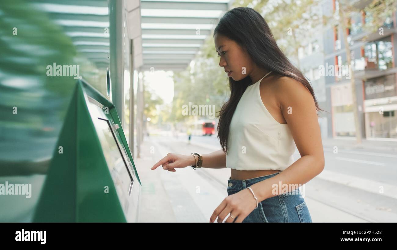 Young woman buying ticket at public transport stop Stock Photo - Alamy