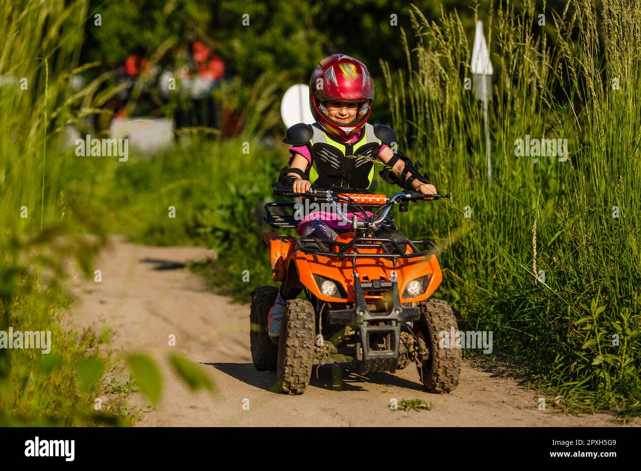 The little girl rides a quad bike. A mini quad bike is a cool girl in a ...