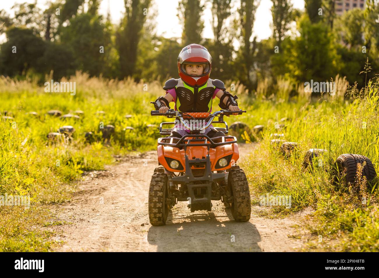 Little girl riding ATV quad bike in race track Stock Photo - Alamy