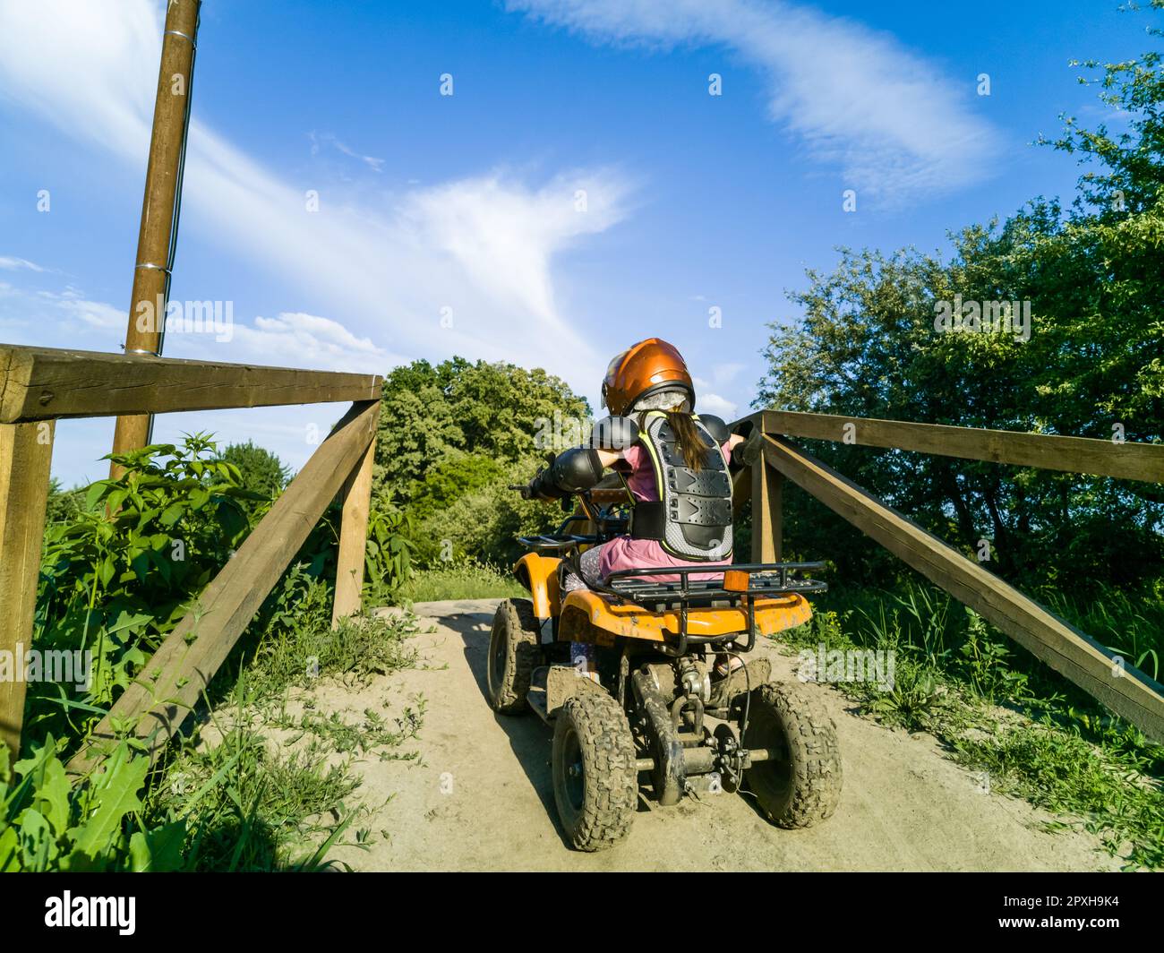 The little girl rides a quad bike. A mini quad bike is a cool girl in a ...