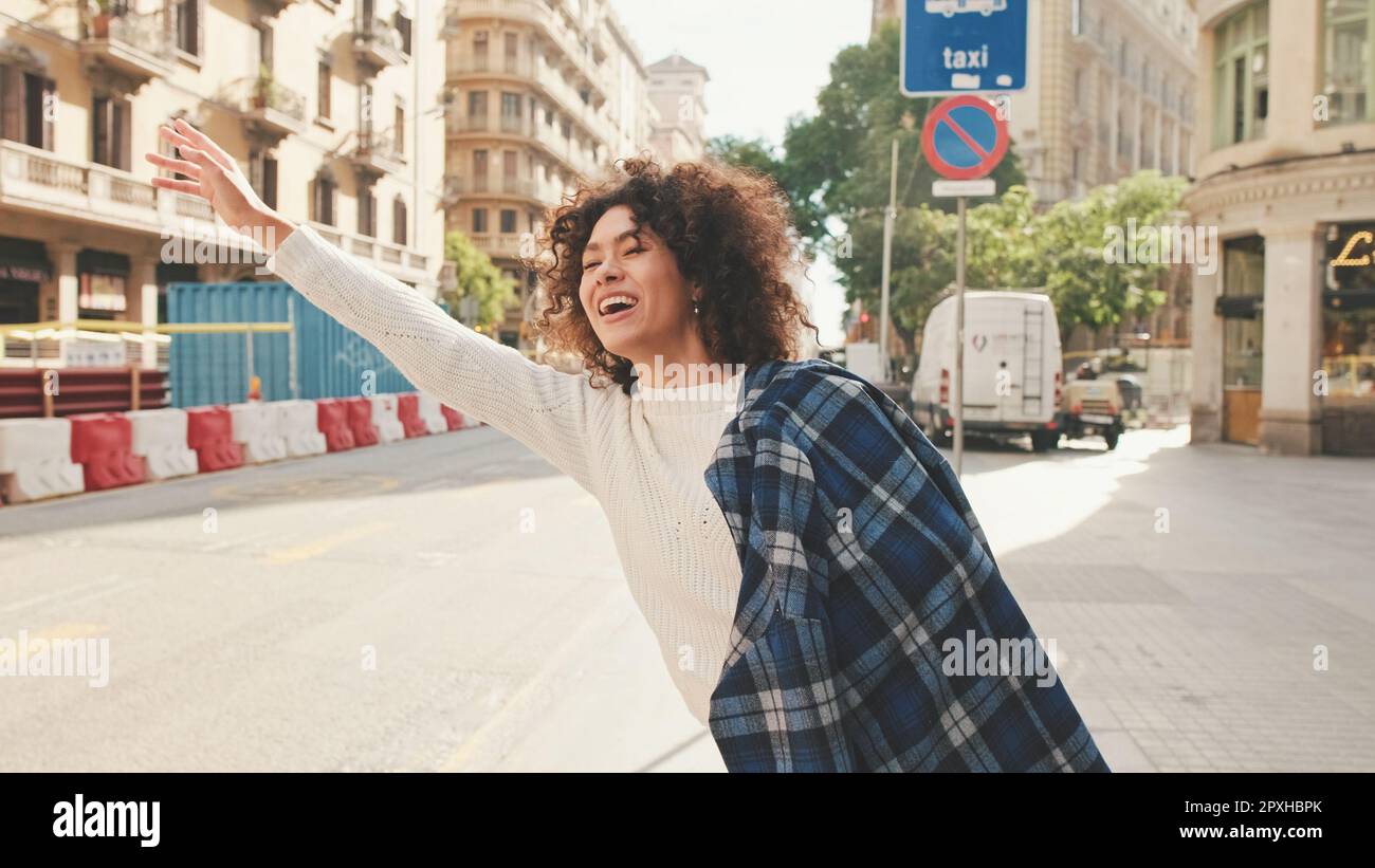 Young woman is calling a taxi. Girl stands next to the road raises her ...