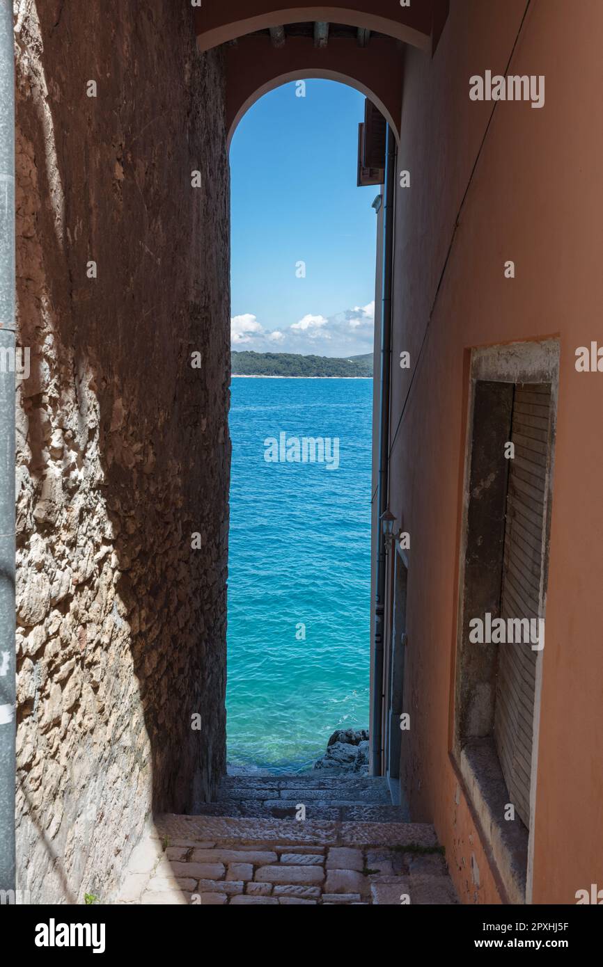 Adriatic Sea seen through narrow stone archway by buildings in the ...