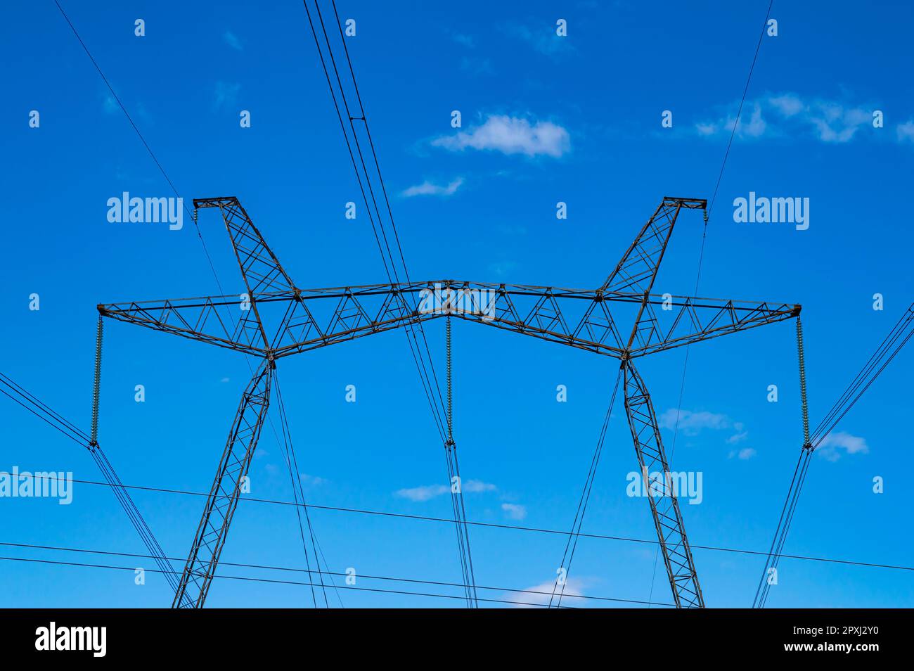 Tower with high-voltage energy transmission wires against the blue sky ...