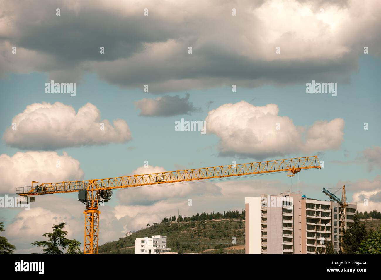 A large construction crane stands in the foreground of a cityscape ...