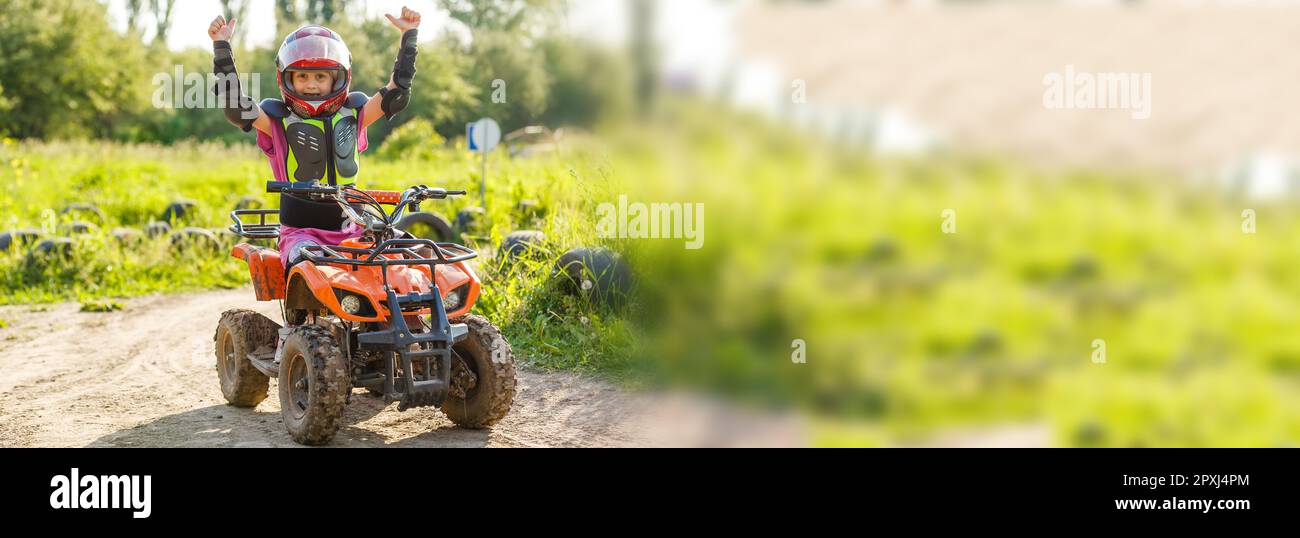 The little girl rides a quad bike. A mini quad bike is a cool girl in a ...