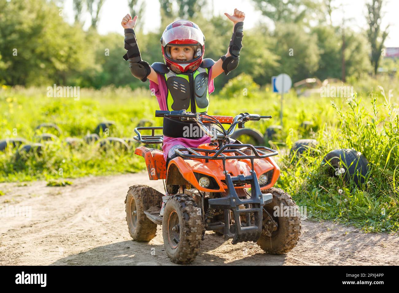 The little girl rides a quad bike. A mini quad bike is a cool girl in a ...