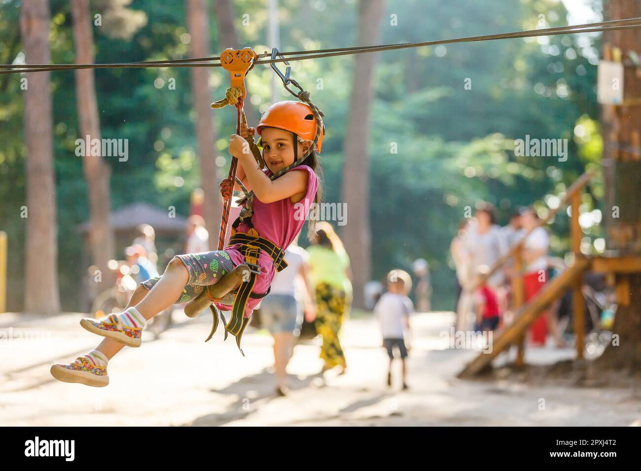 Happy school girl enjoying activity in a climbing adventure park on a ...