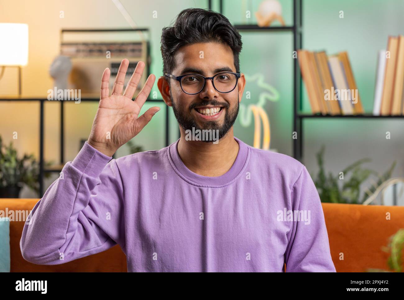 Hello. Indian handsome man smiling friendly at camera and waving hands ...