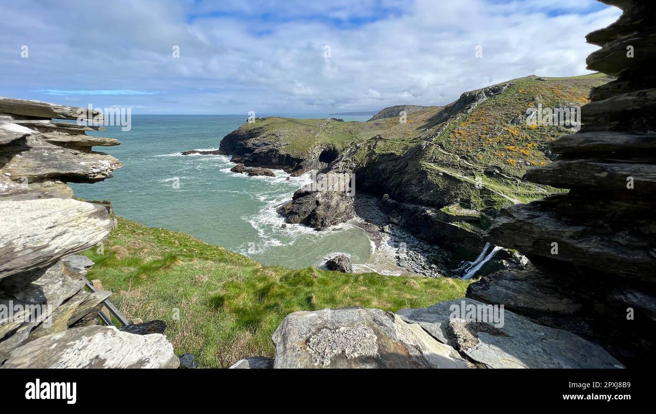 A serene view of a beach with clear blue ocean water and rocky ...