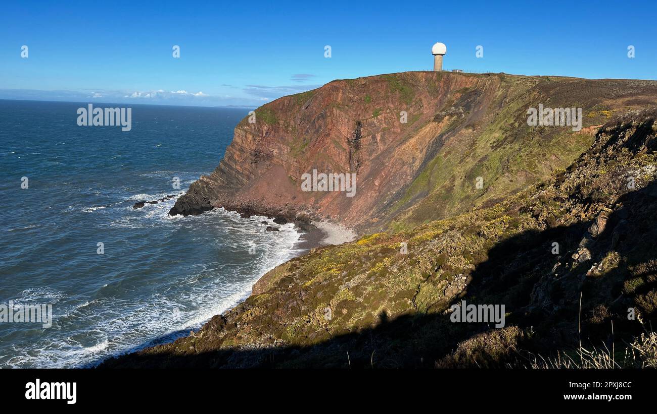 A lighthouse perched atop a steep cliff overlooking the expansive ocean ...