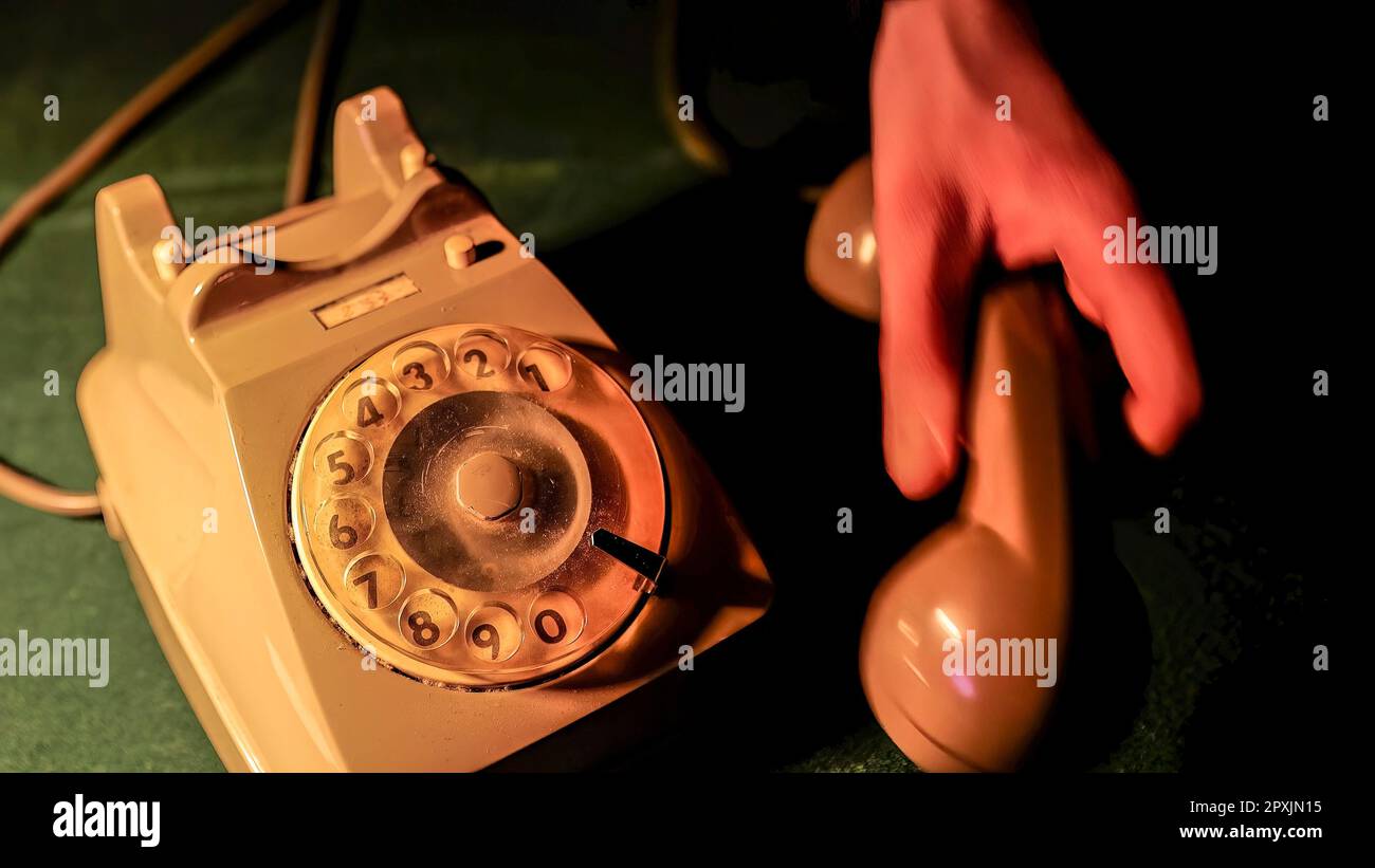 Hands of a man placing the receiver of an old vintage phone into its ...
