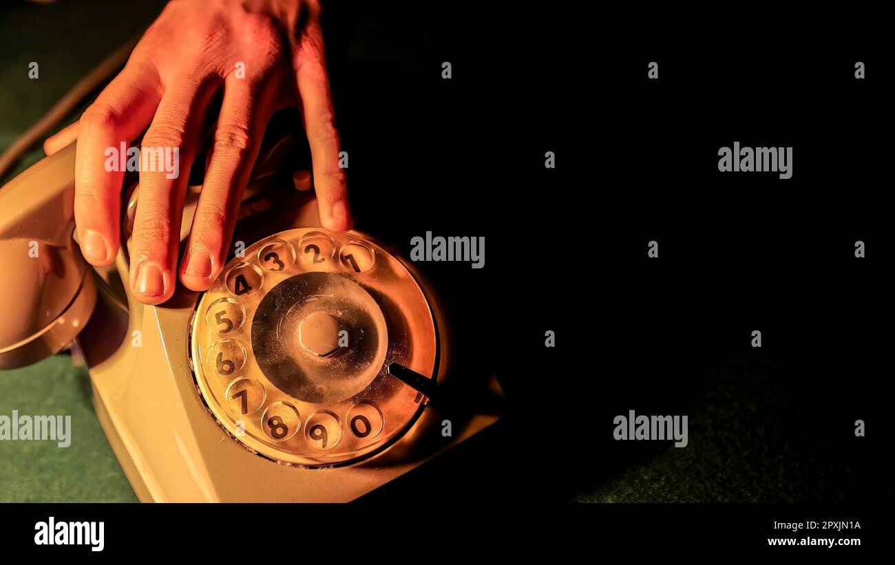 Hands of a man placing the receiver of an old vintage phone into its ...