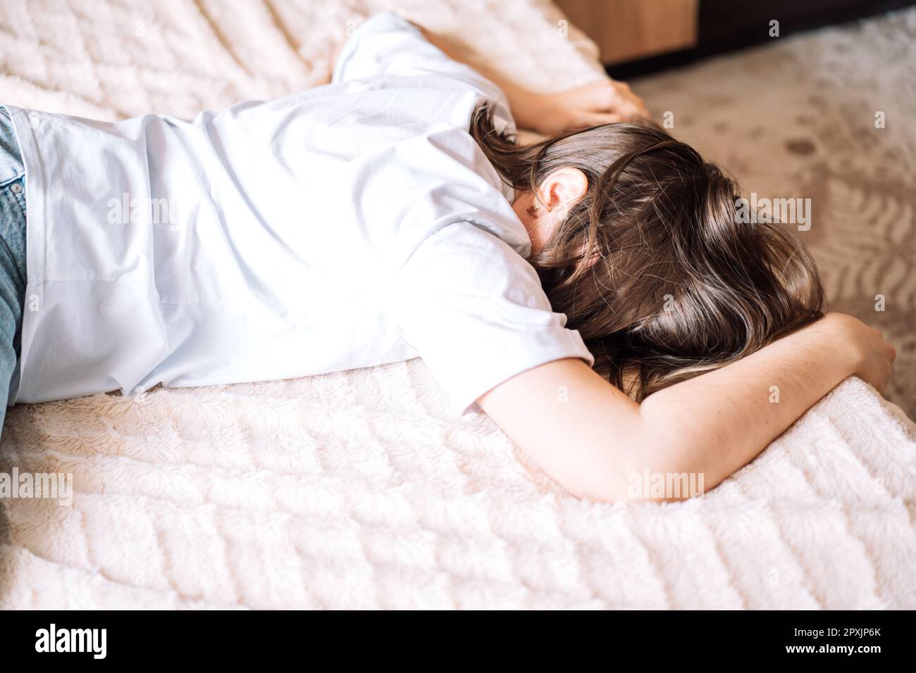 Upset lady in a white t-shirt lies on the bed Stock Photo - Alamy