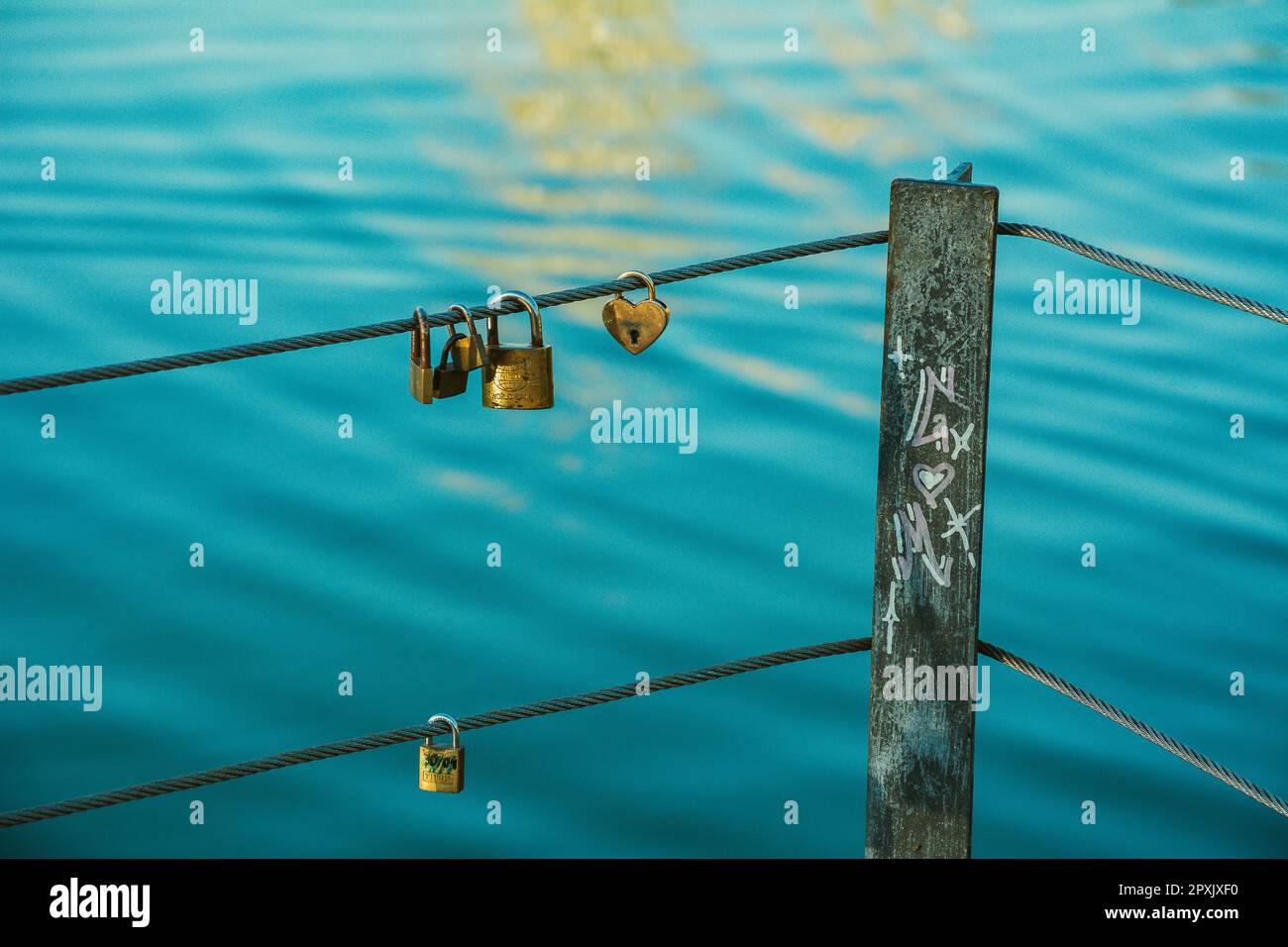 Padlocks closed in sign of eternal love over blue waters in a calm lake ...