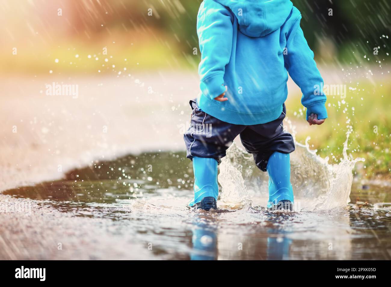 Small child jumping through puddles in nature in spring. Concept of the ...