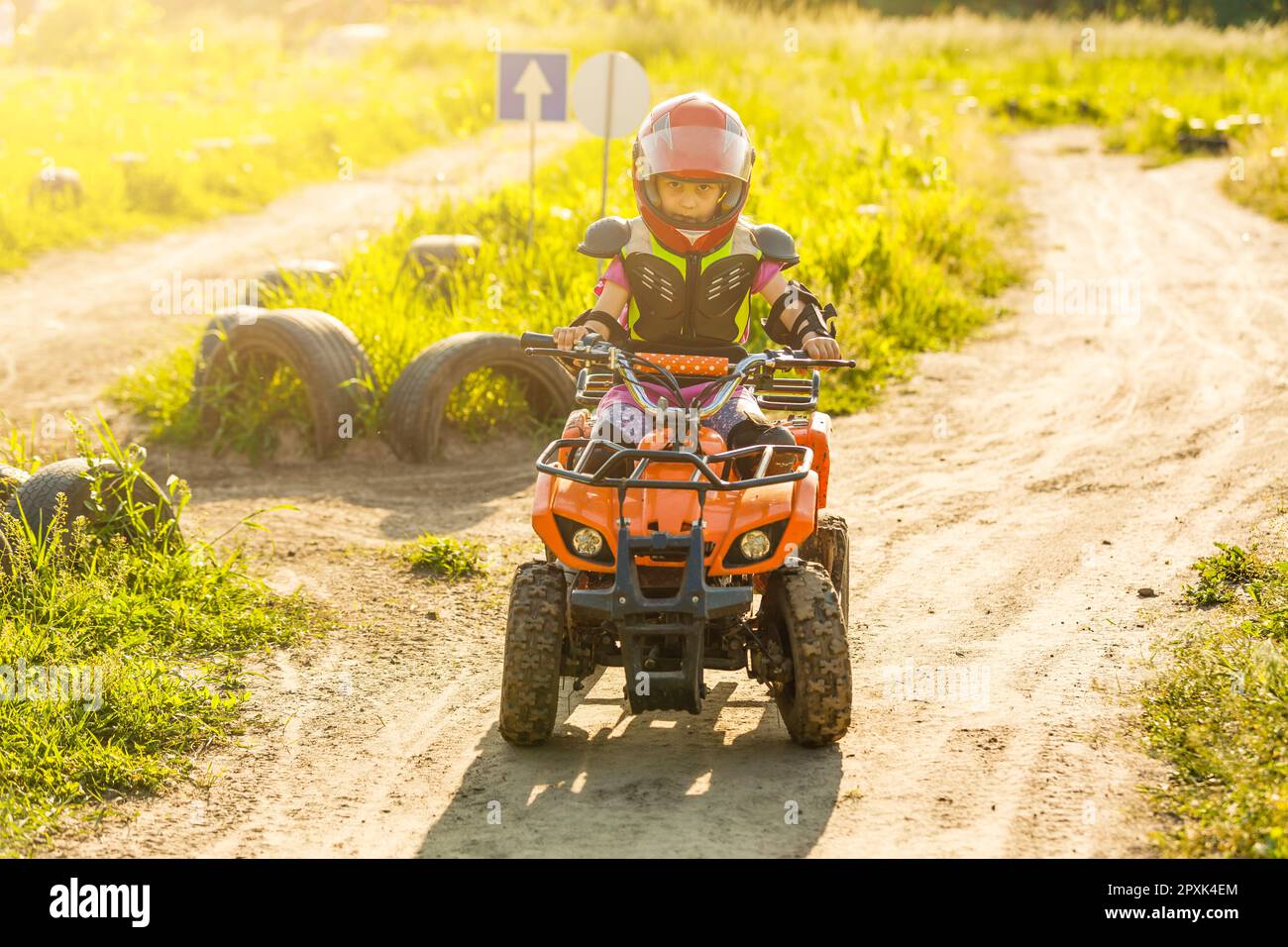 Little girl riding ATV quad bike in race track Stock Photo - Alamy
