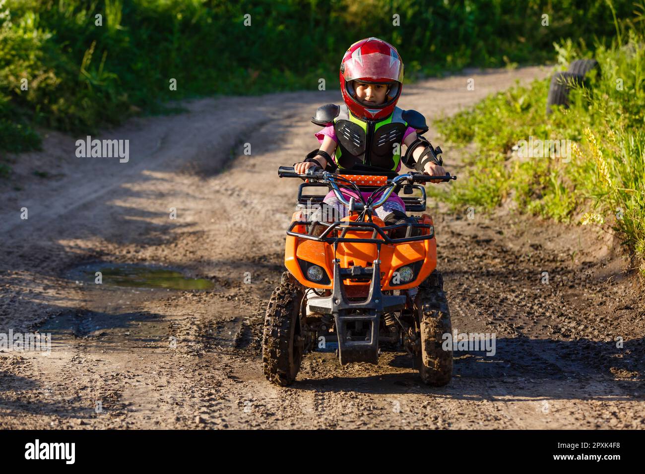 Little girl riding ATV quad bike in race track Stock Photo - Alamy