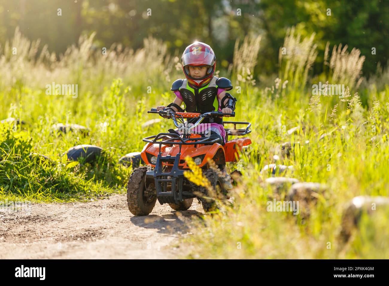 The little girl rides a quad bike. A mini quad bike is a cool girl in a ...