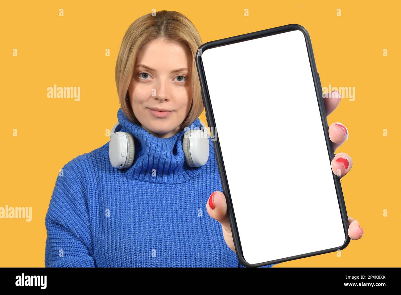 Positive millennial ladie holding smartphone with white blank screen ...