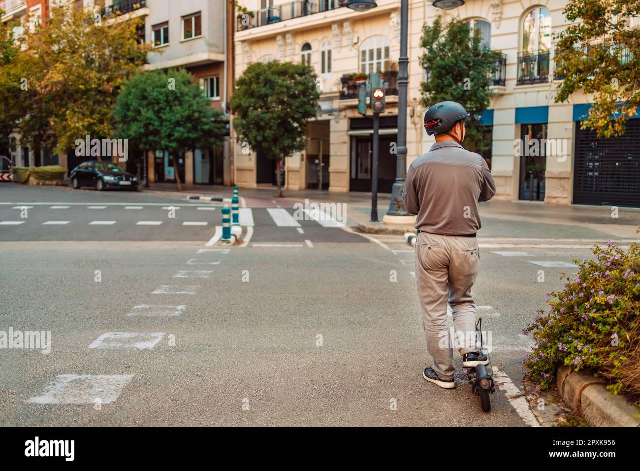Back view of young man on vacation having fun driving electric scooter ...