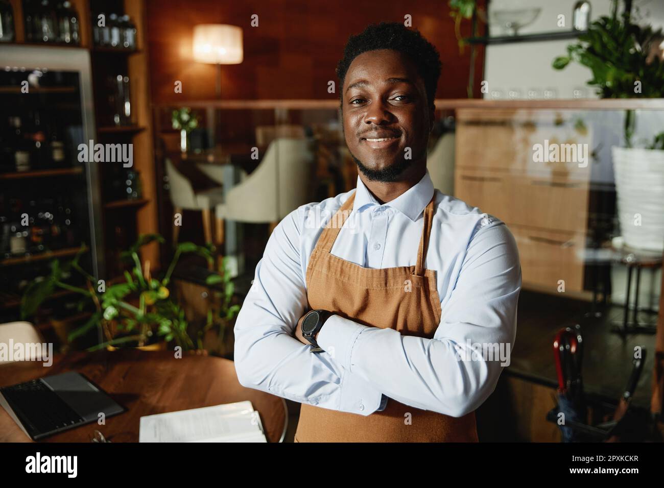 Portrait of young African American waiter smiling at camera standing ...