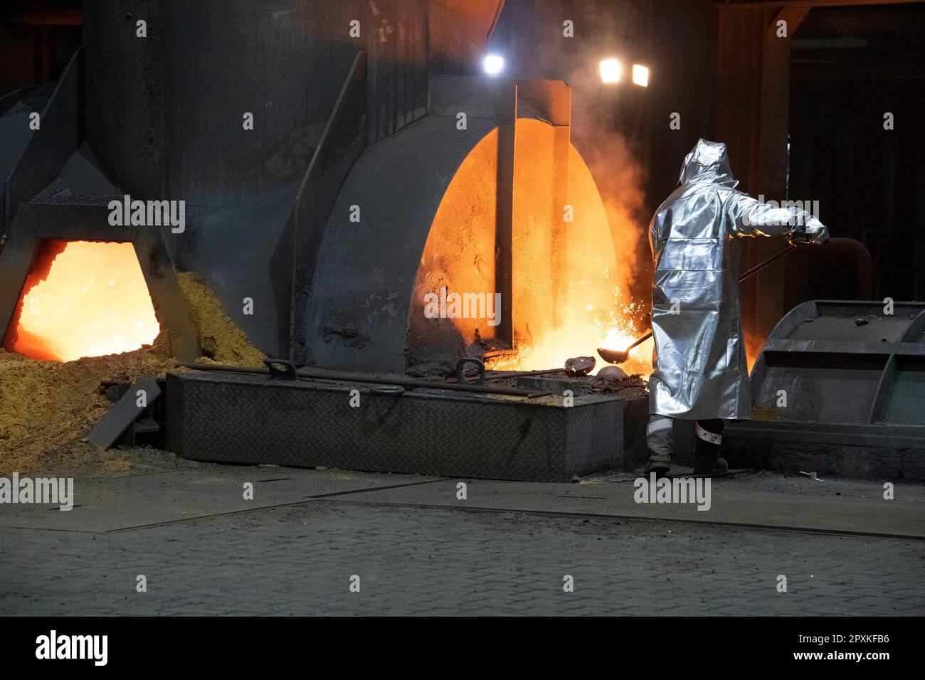 A steelworker takes a sample from the tapping of the blast furnace ...