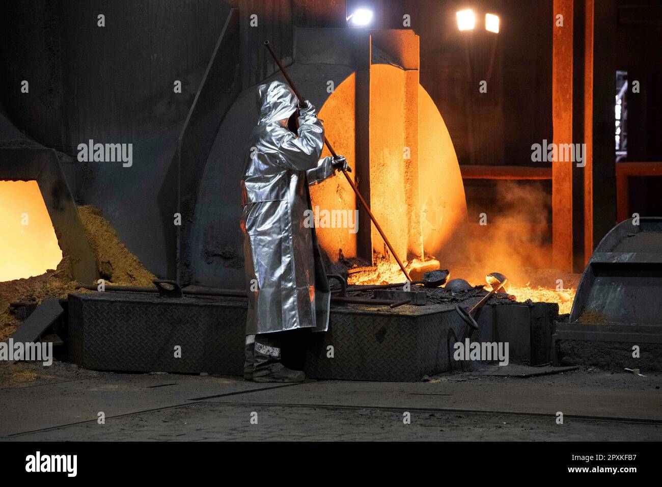 A steelworker takes a sample from the tapping of the blast furnace ...