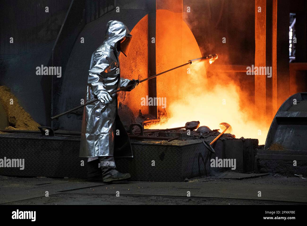 A steelworker takes a sample from the tapping of the blast furnace ...