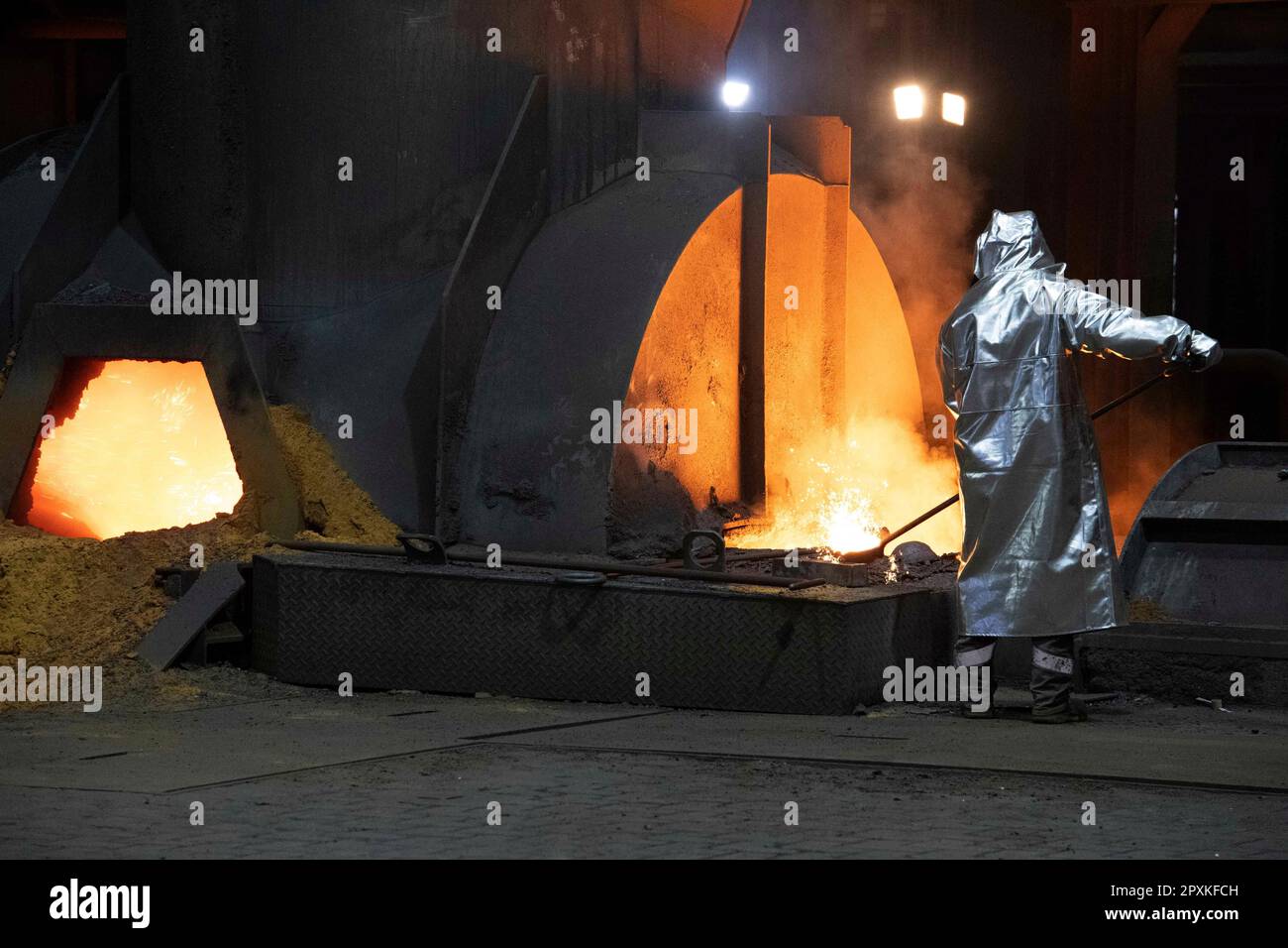 A steelworker takes a sample from the tapping of the blast furnace ...