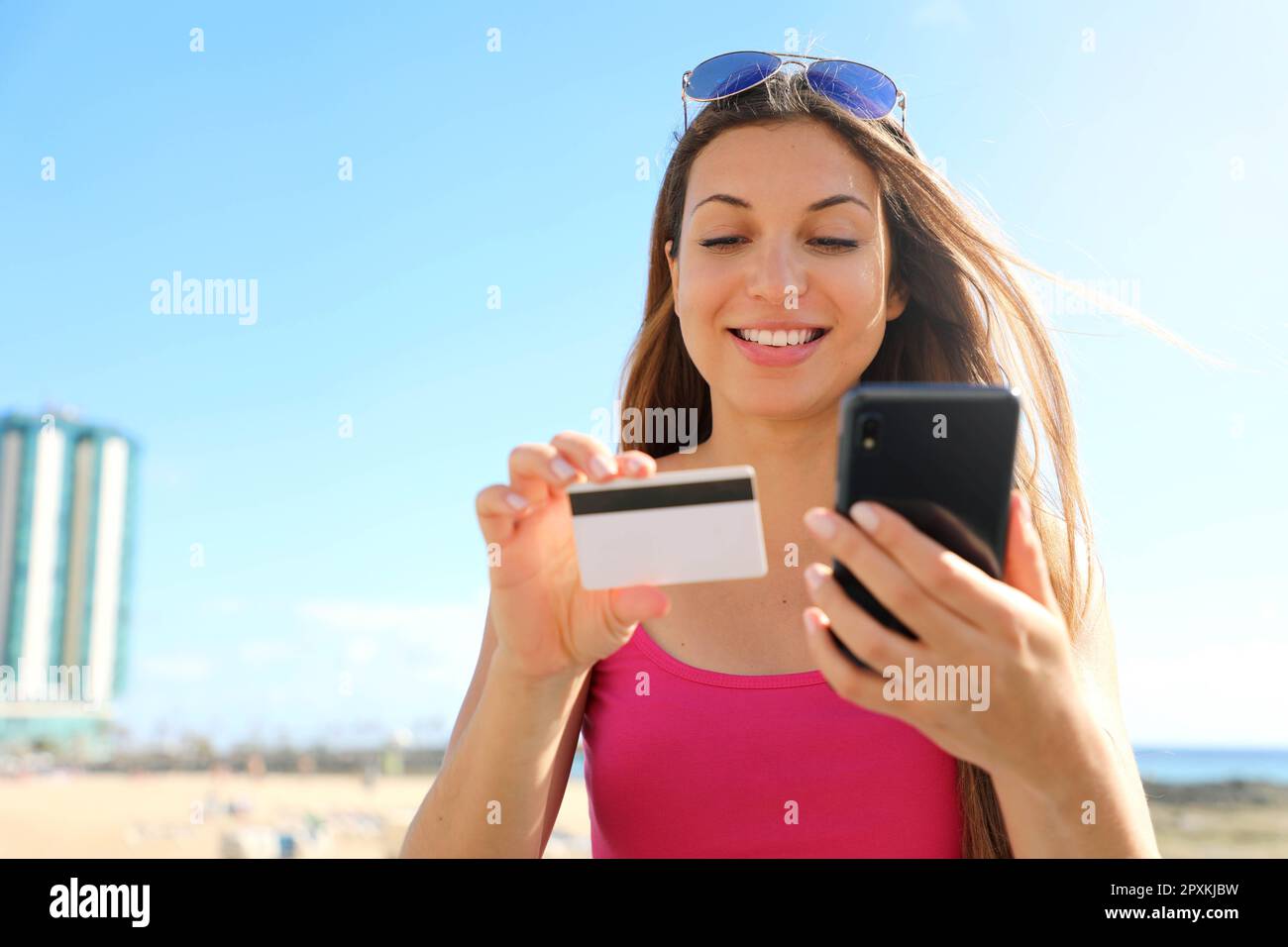 Close-up of cute young woman reading credit card number for payment ...