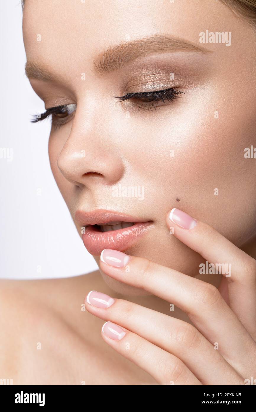Beautiful young girl with a light natural make-up and French manicure ...