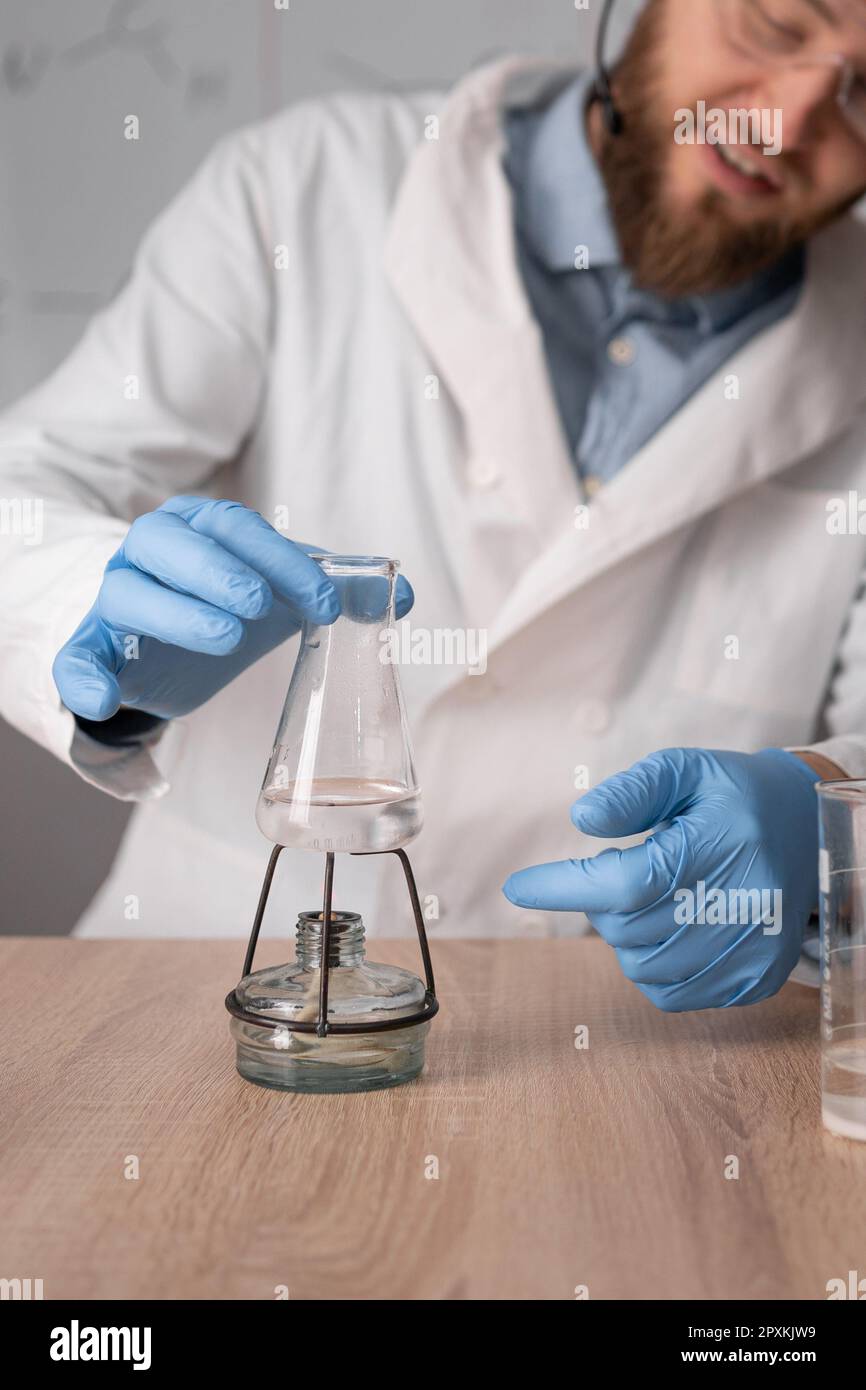 Chemistry teacher conducting a chemical experiment by heating a liquid ...
