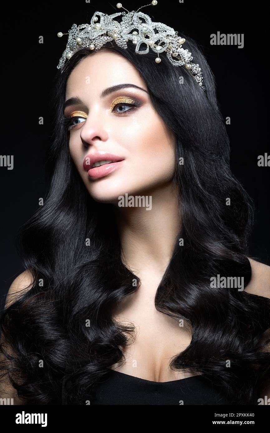 Beautiful dark-haired woman with a crown of precious stones, curls and ...