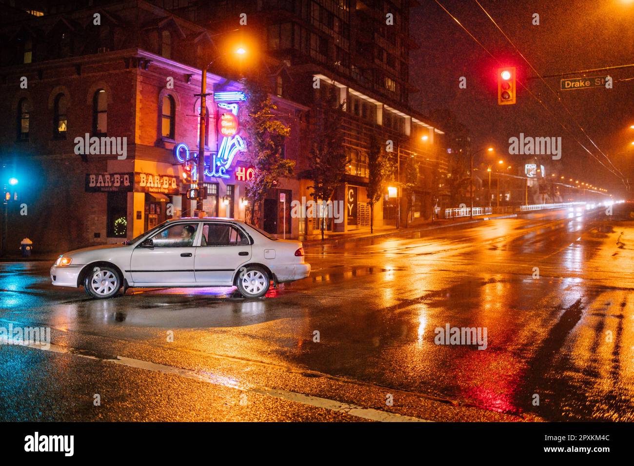 A bustling city street at night illuminated by street lamps and the ...